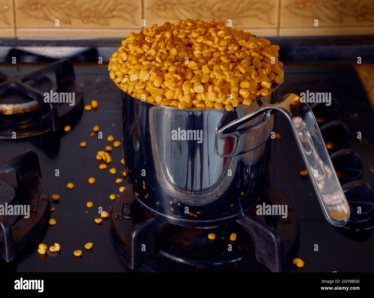 Boiled peas in a stainless saucepan with grains scattered over the gas ...