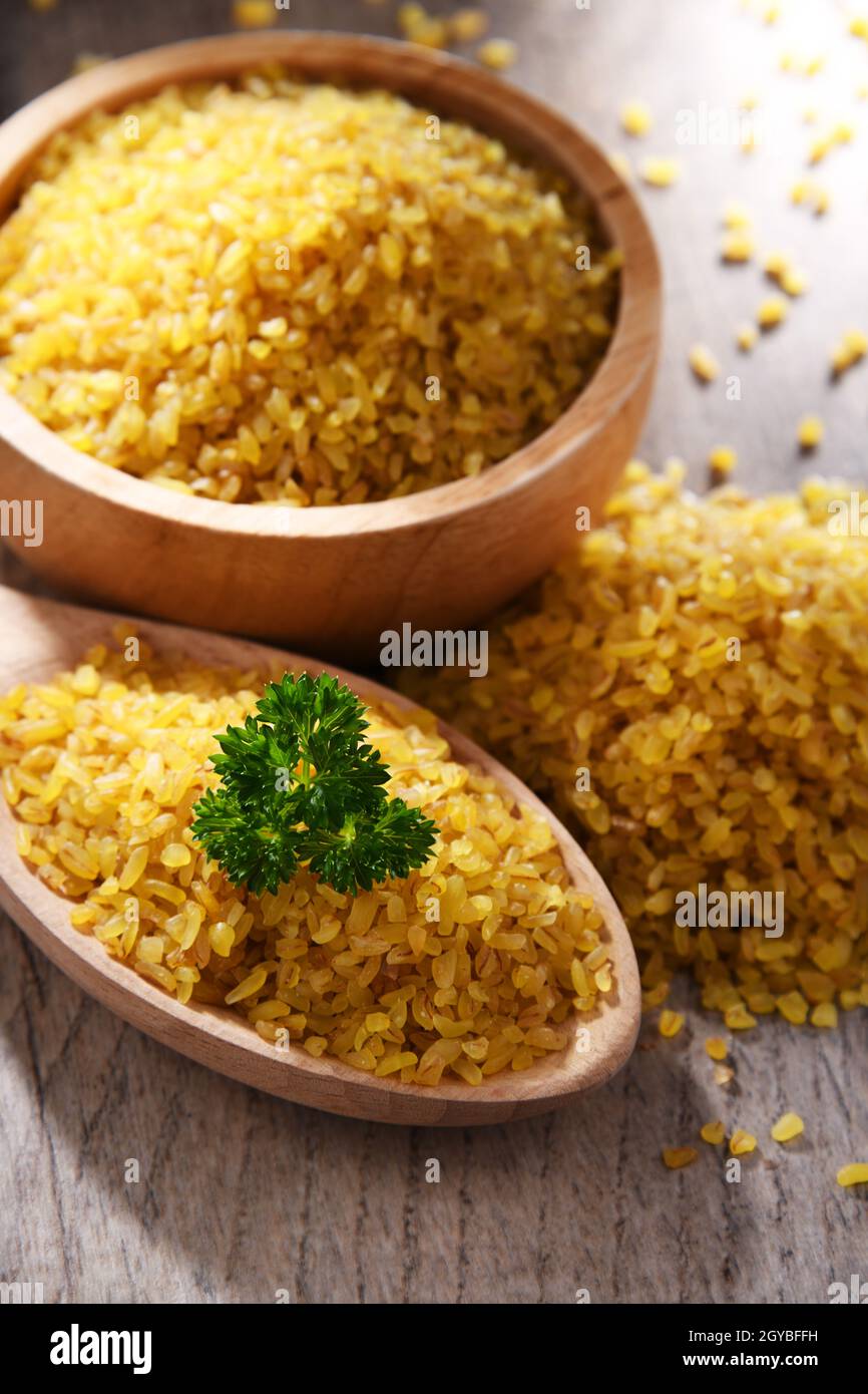 Composition with a bowl and spoon of uncooked bulgur on a table Stock ...