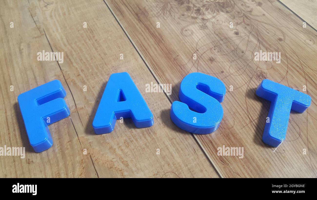 Plastic colored alphabets making words are placed on a wooden floor ...
