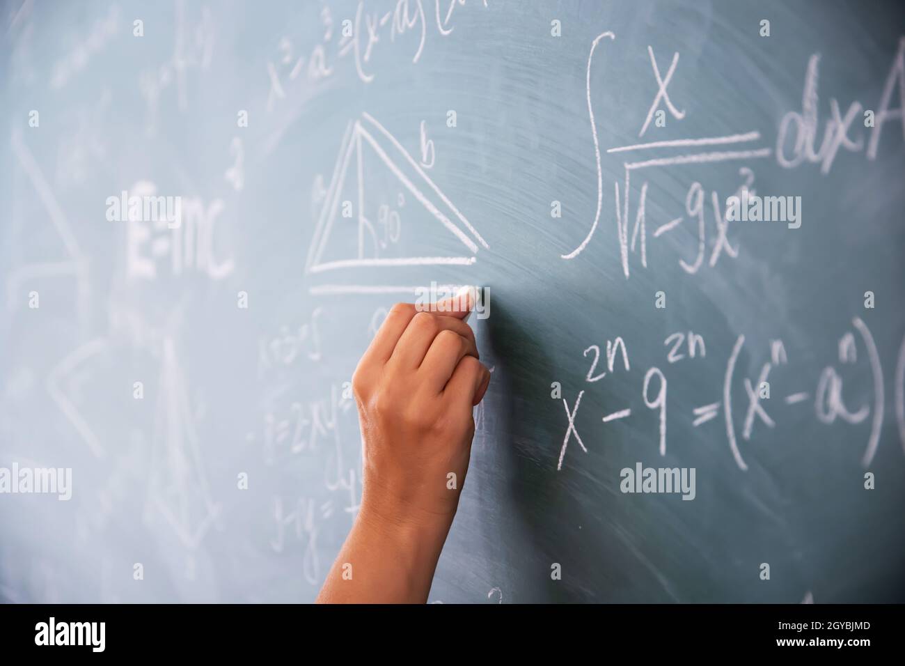Close-up shot of a hand holding chalk and writing mathematical ...