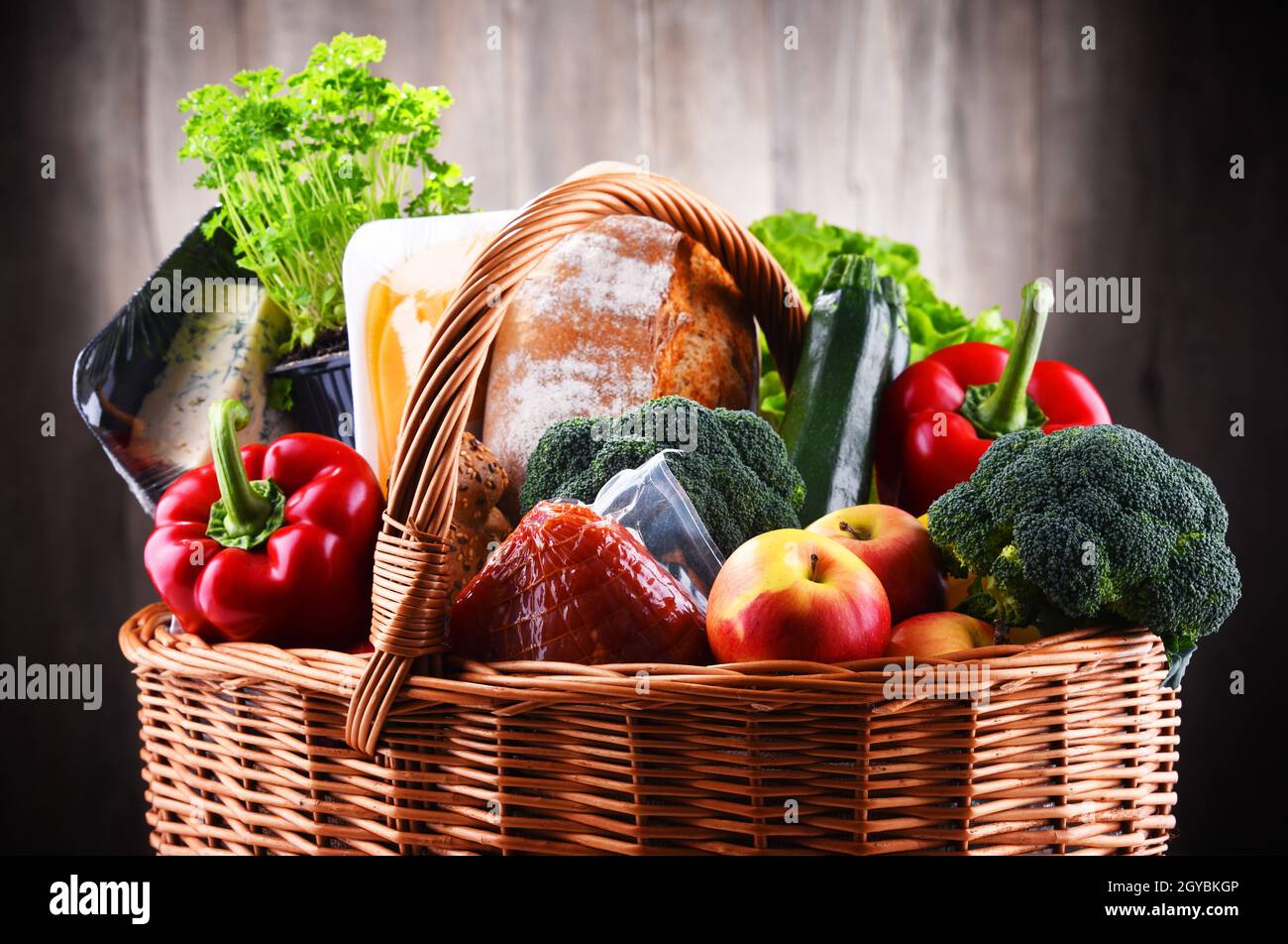 Wicker basket with assorted grocery products including fresh vegetables ...