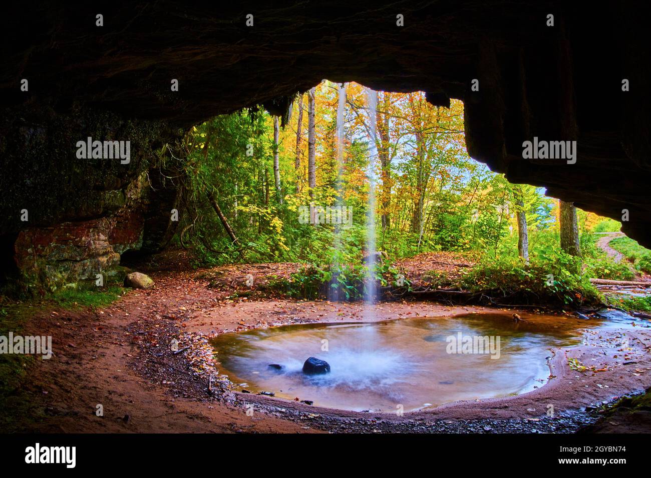 Cliff overhand with straight waterfall outside and a shallow basin ...
