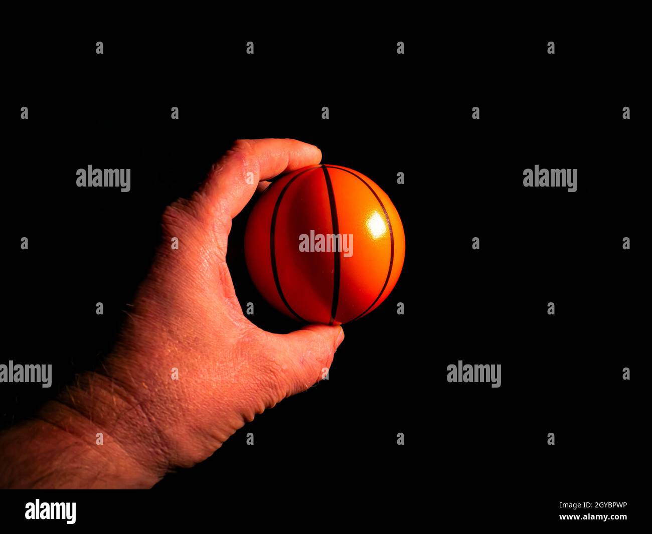 Basketball ball in hand on a black background. Mans hand. Sports ...