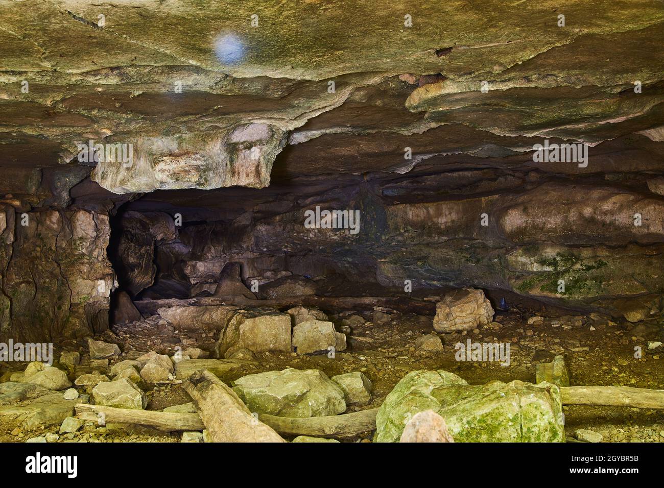 Nearly flat roofed cave with large rocks strewn across the ground Stock ...