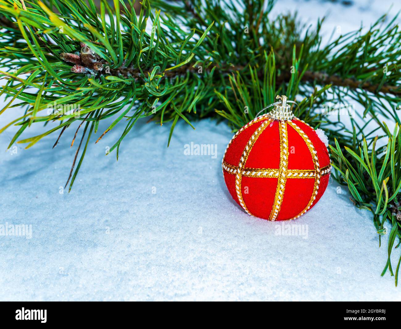 Red ball Christmas tree toy with gold edging on the snow. Merry ...