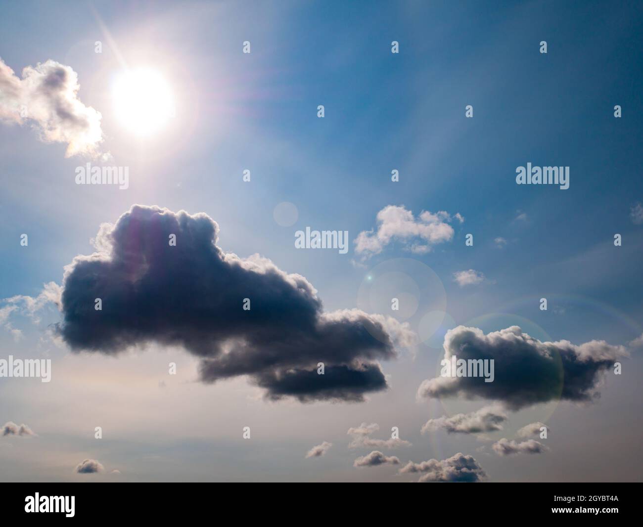 Sun on a background of blue sky with rain clouds. Sun glare. Blue sky ...