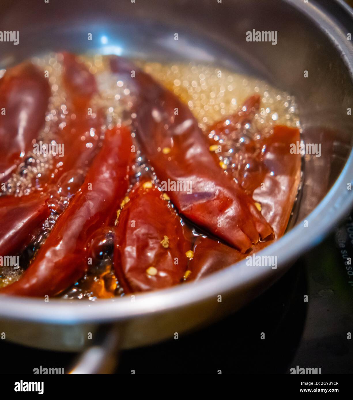 Red dry peppers boiling in oil inside cooking pot Stock Photo - Alamy