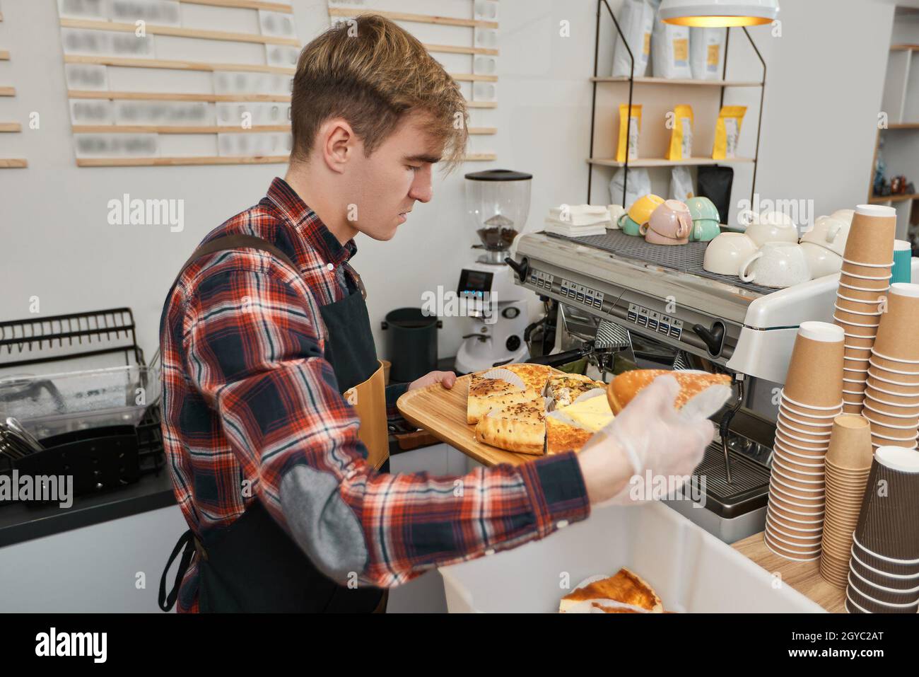 happy male worker in apron sells fresh bakery products in coffee shop ...