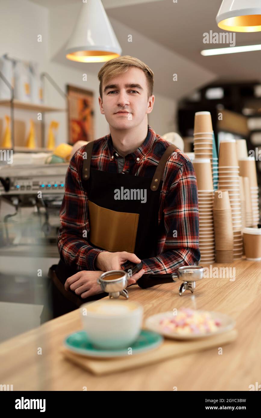 happy male waiter in apron in coffee shop, barista is happy to work in ...