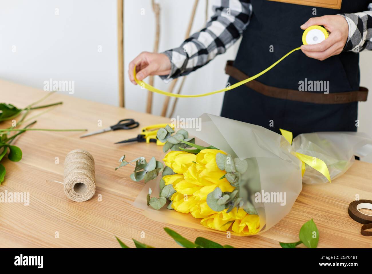 Florist woman makes a bouquet of fresh yellow tulips. Floral design ...