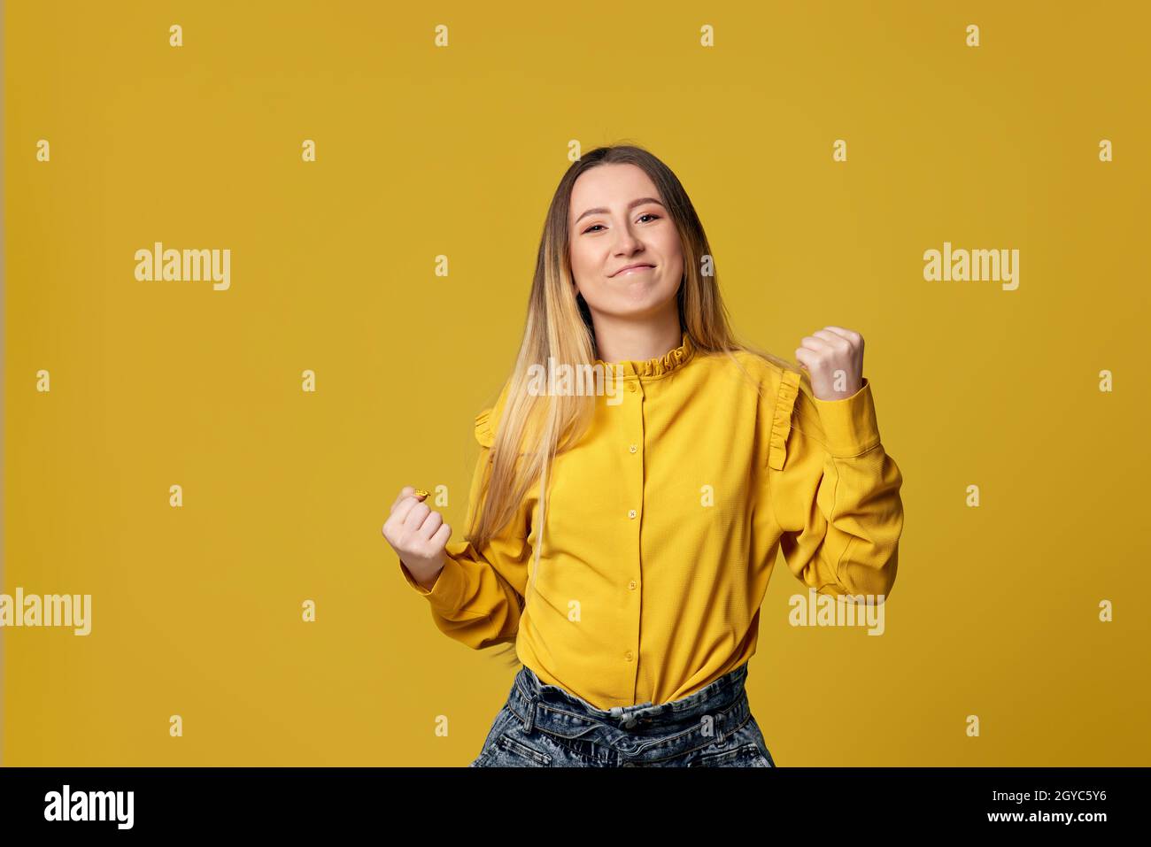 young woman showing victory gesture on yellow background. Human ...