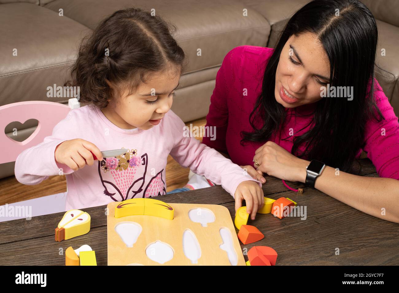 Mother Encouraging 3 Year Old Daughter Playing With Puzzle Stock Photo mother-encouraging-3-year-old-daughter-playing-with-puzzle-stock-photo