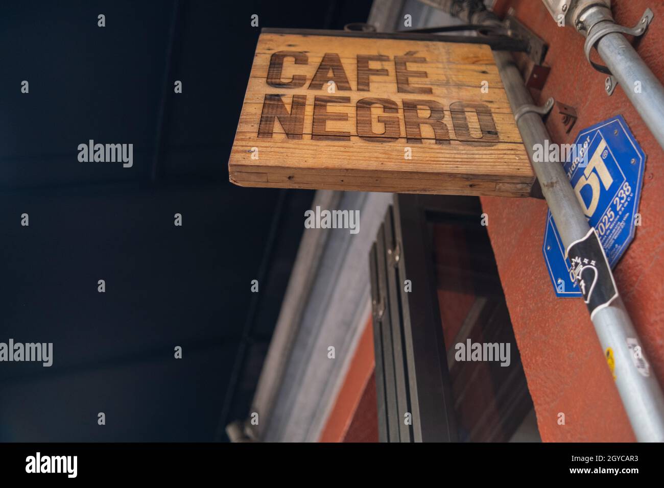Wooden sign with Spanish text hanging from red wall Stock Photo - Alamy