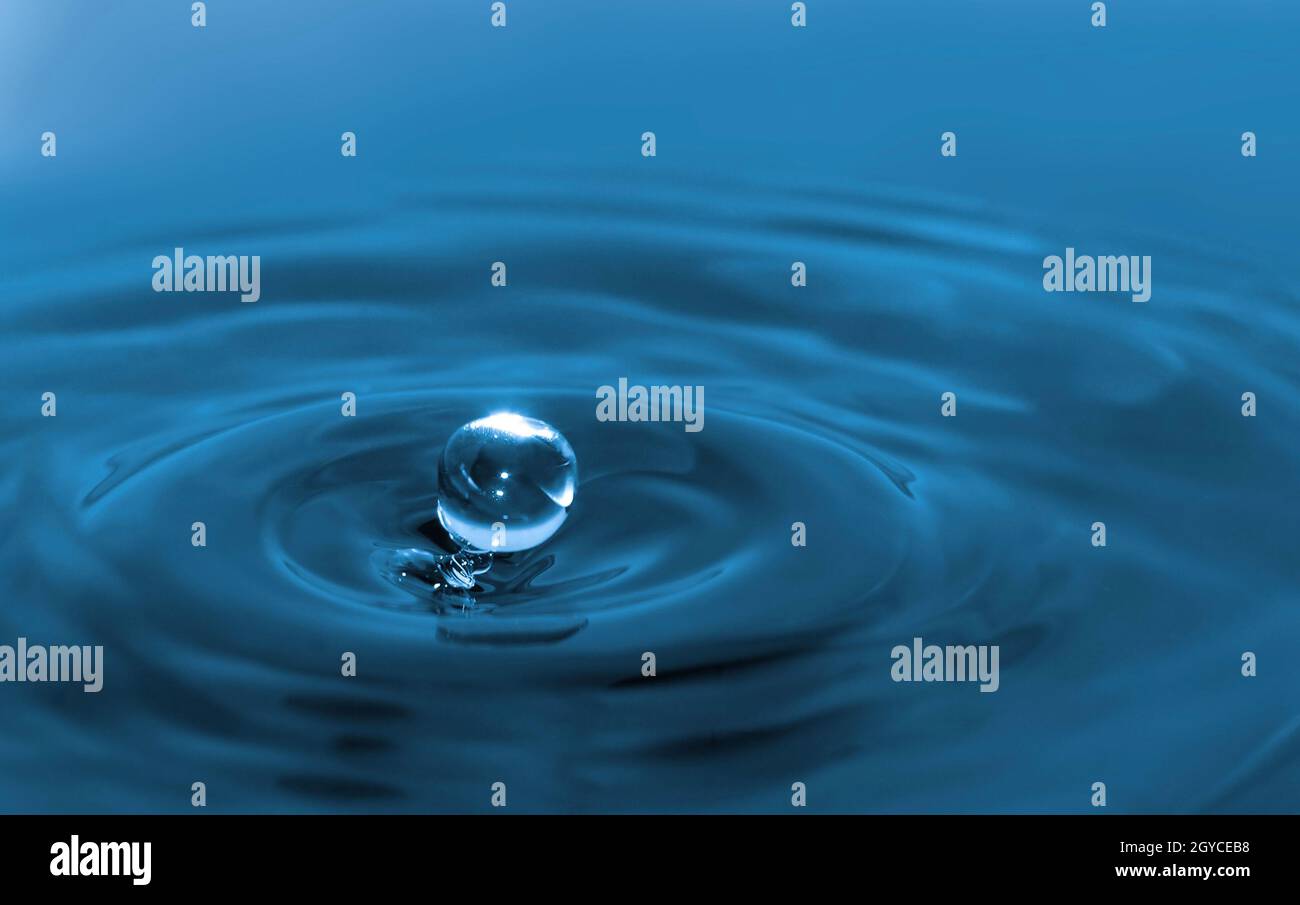 Water drop bouncing off the water surface Stock Photo - Alamy