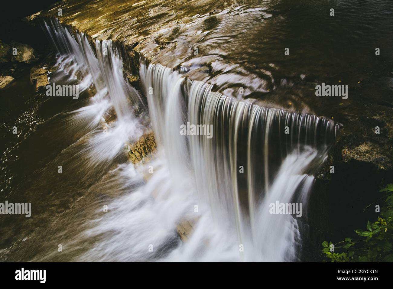 Close view at angle of edge of waterfalls flowing into river Stock ...