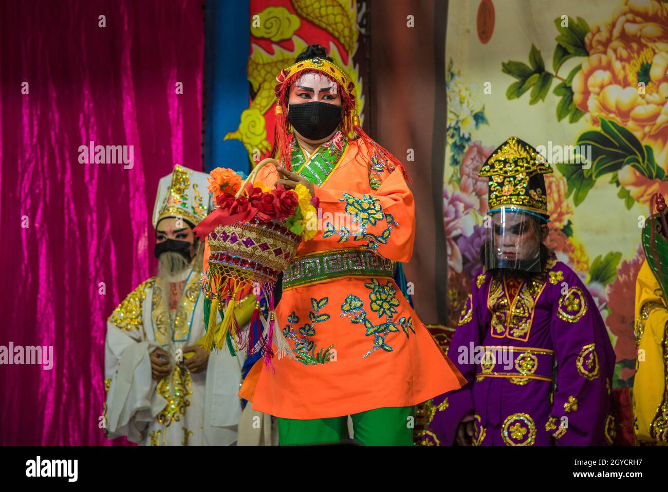 A member of the Chinese opera troupe wearing a face mask as a ...