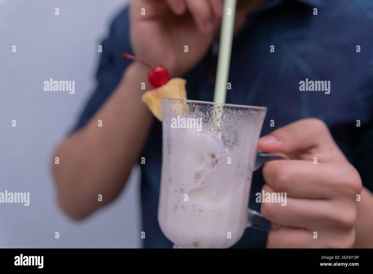 Man holding and drinking tasty vanilla milkshake with straw Stock Photo ...