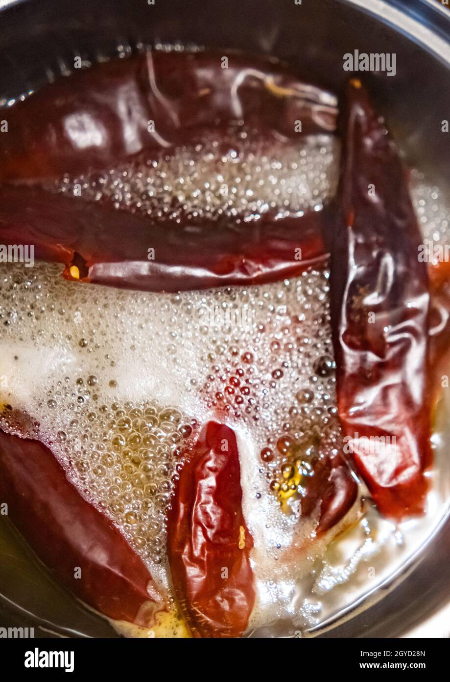 Red dry peppers boiling in oil inside cooking pot Stock Photo - Alamy