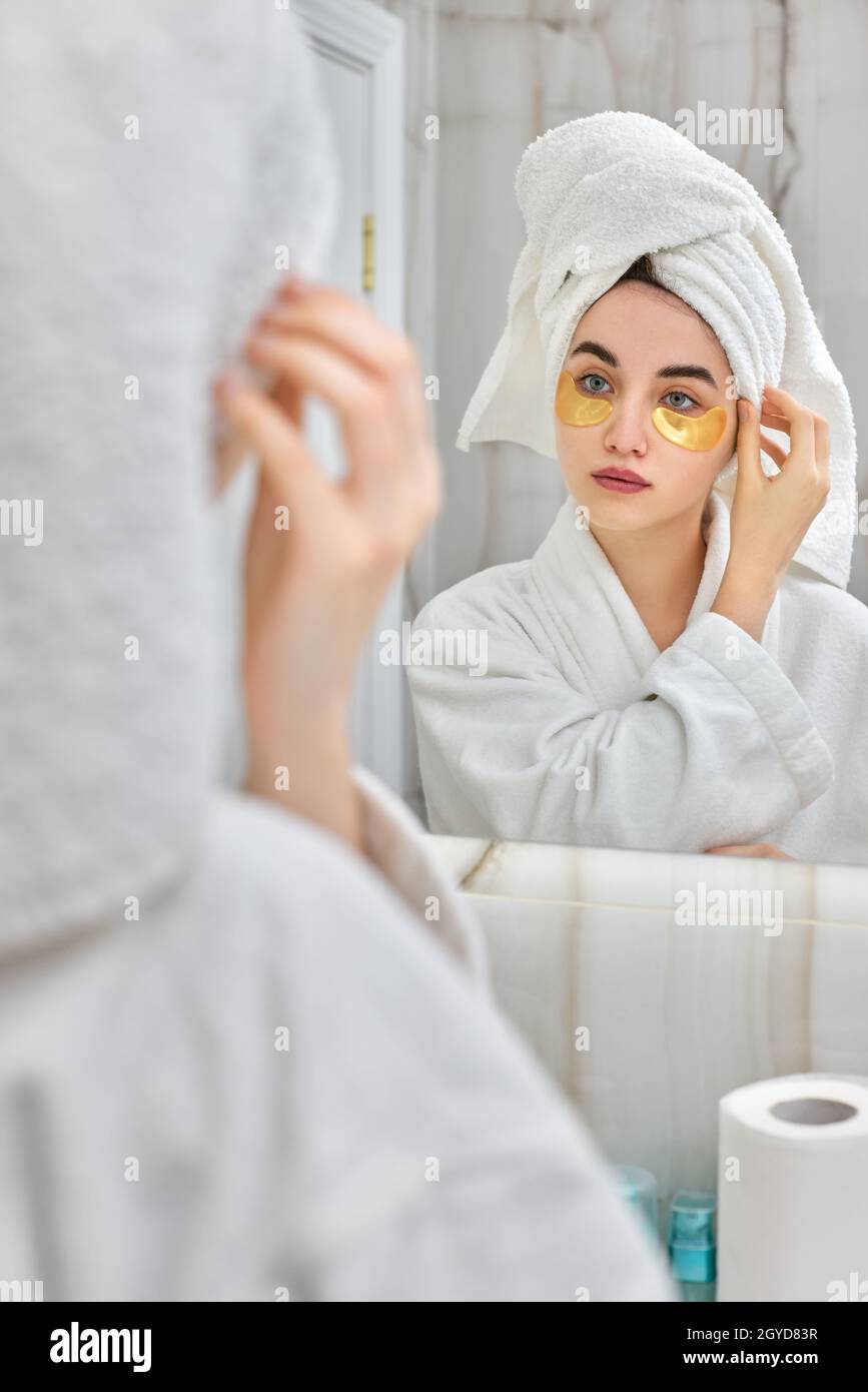 Beautiful Woman With Eye Patches In White Bathrobes In Front Of Mirror