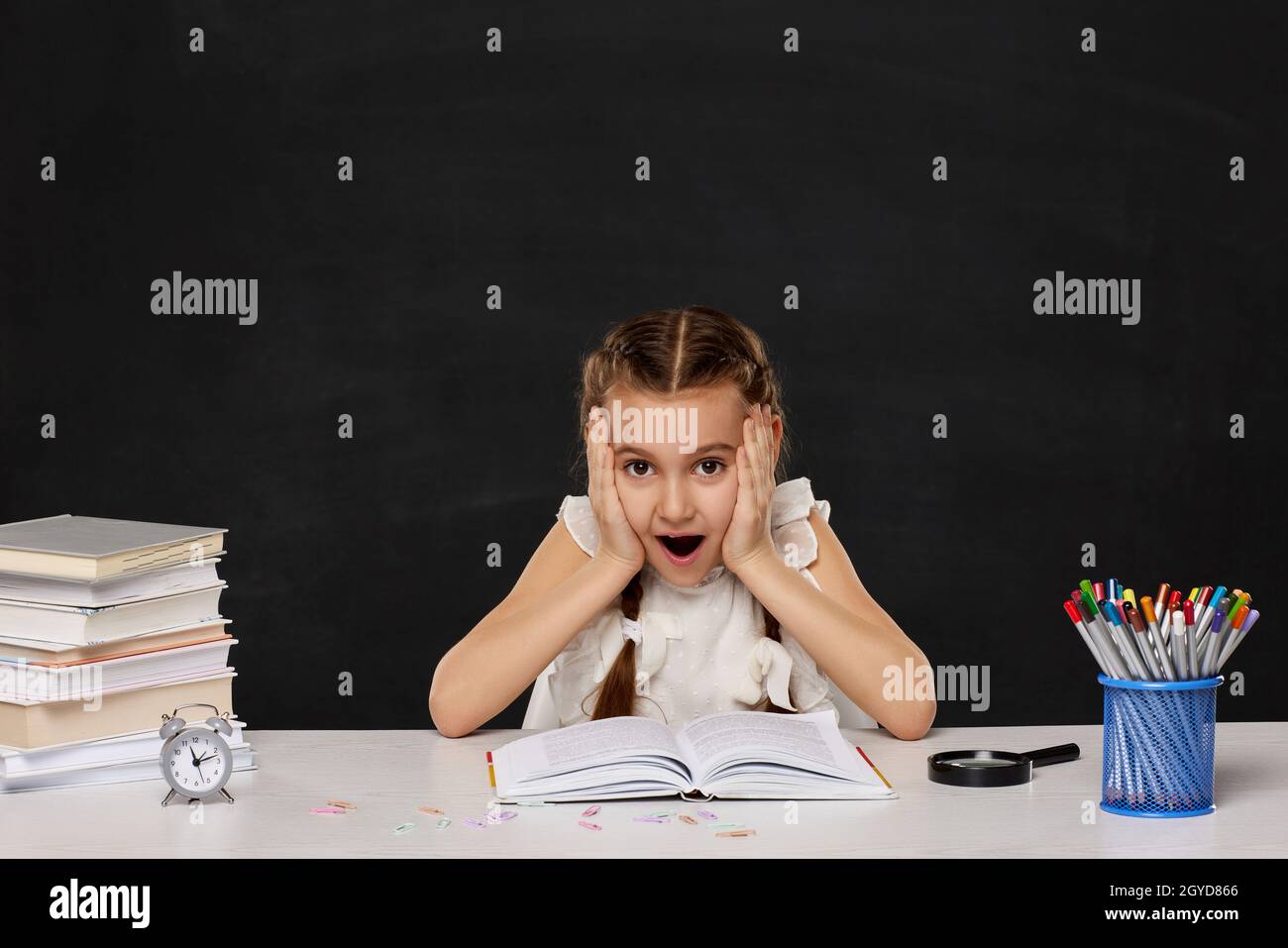 Stressed child girl reading a book in the classroom on background of ...