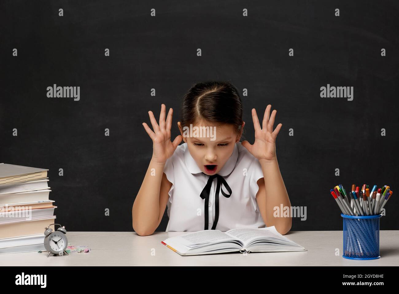 Stressed child girl reading a book in the classroom on background of ...