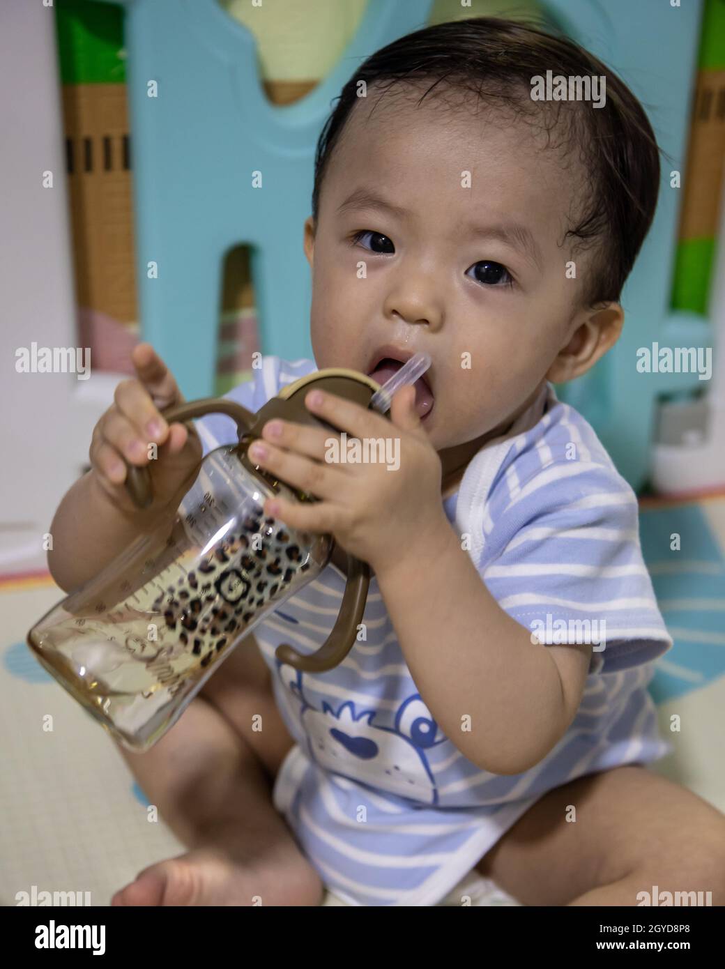 Adorable and joyful Asian Chinese baby boy holding water bottle and ...