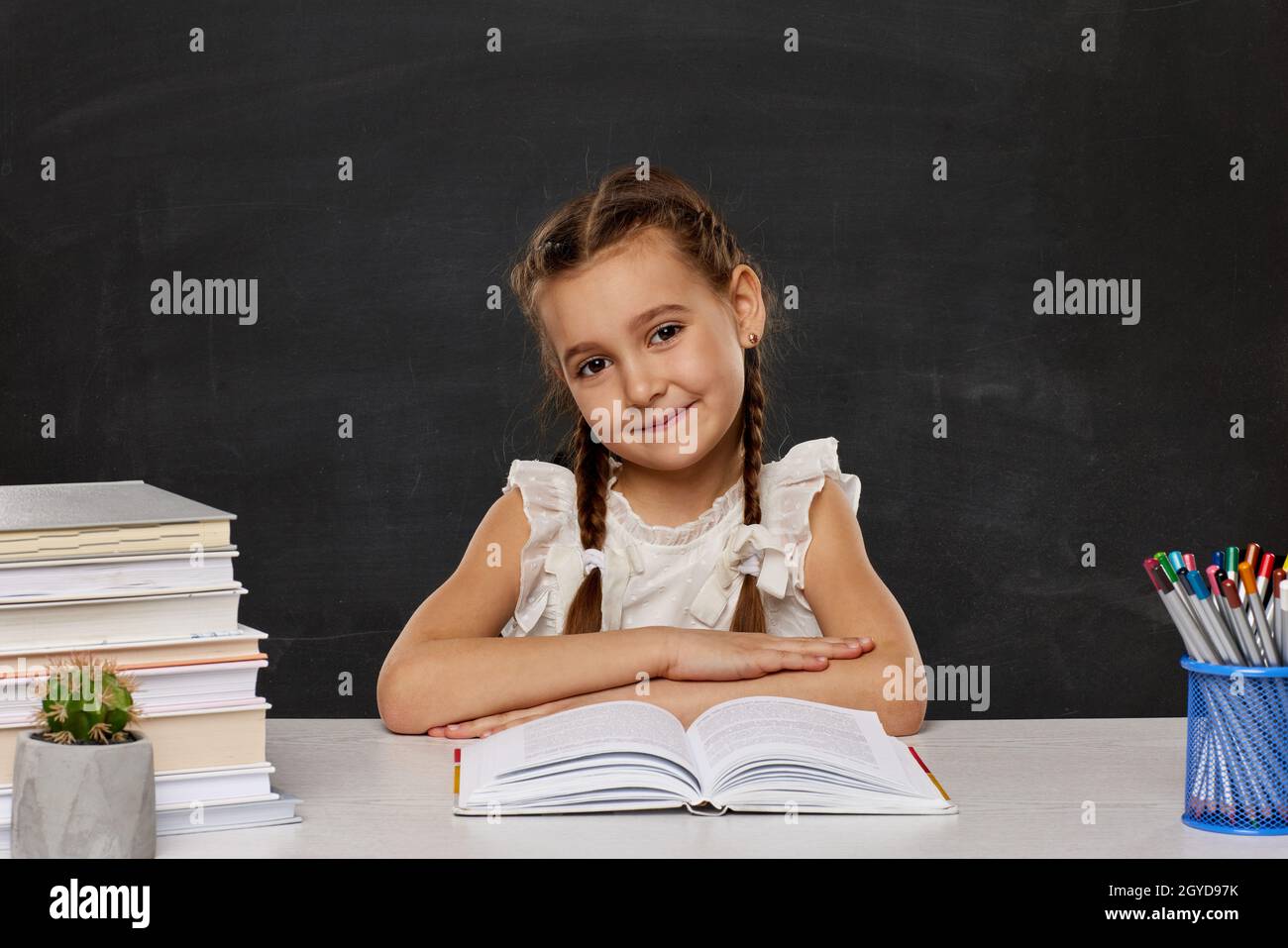 cute little child girl reading a book in the classroom on background of ...