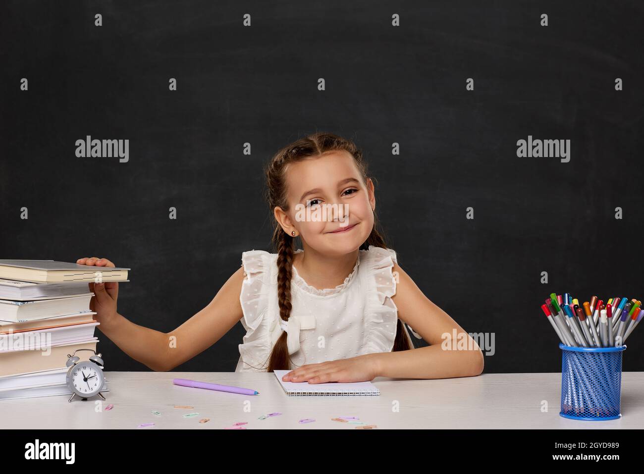 smiling caucasian schoolgirl studying with pile of books in the ...