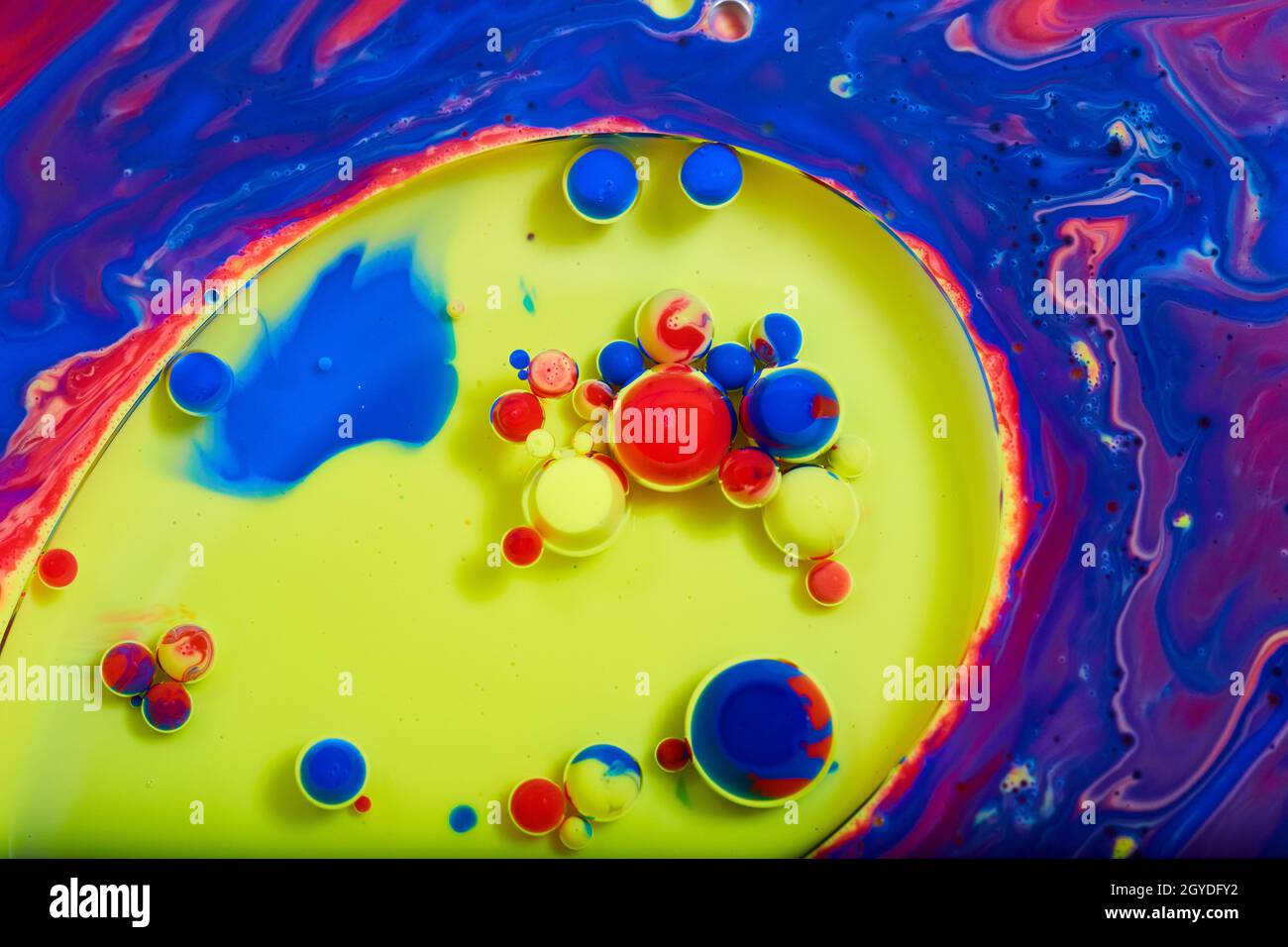 Tiny colorful spheres of red, yellow, and blue on mystical liquid ...