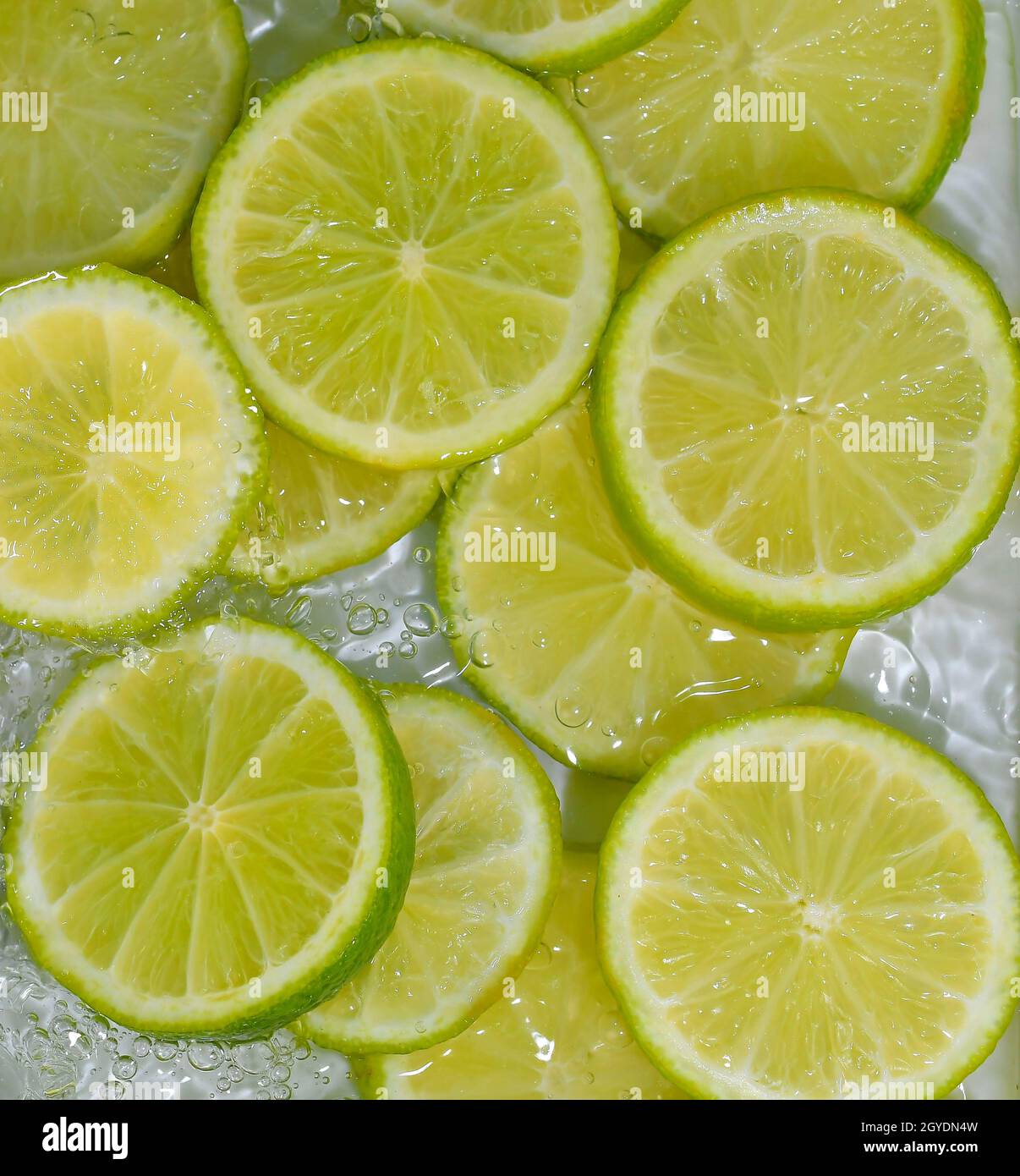 Slices of limes fruit in water on white background. Limes close-up in ...