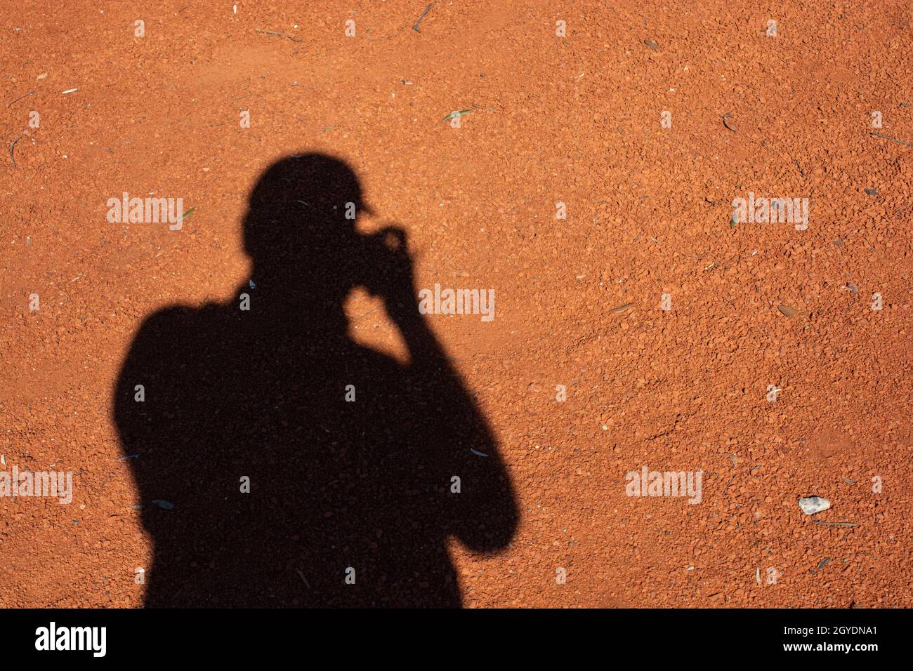 Overhead of a man's shadow on the red sandy ground Stock Photo - Alamy