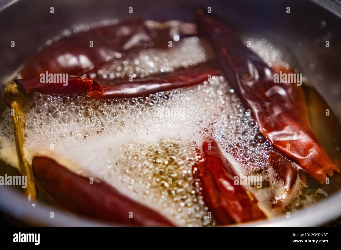 Red dry peppers boiling in oil inside cooking pot Stock Photo - Alamy
