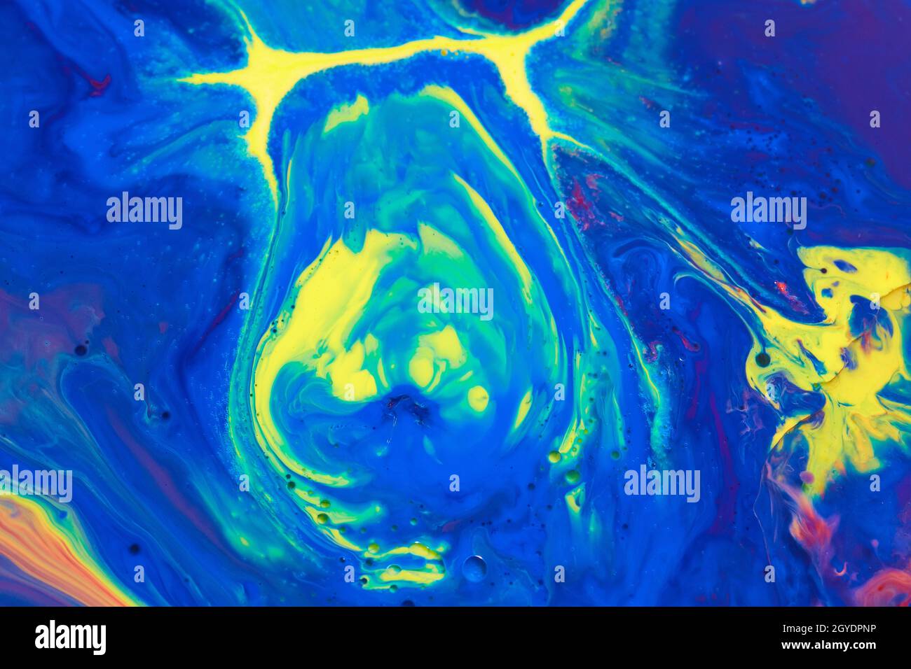Surface of liquid with colorful mix of blue and yellow to make green ...