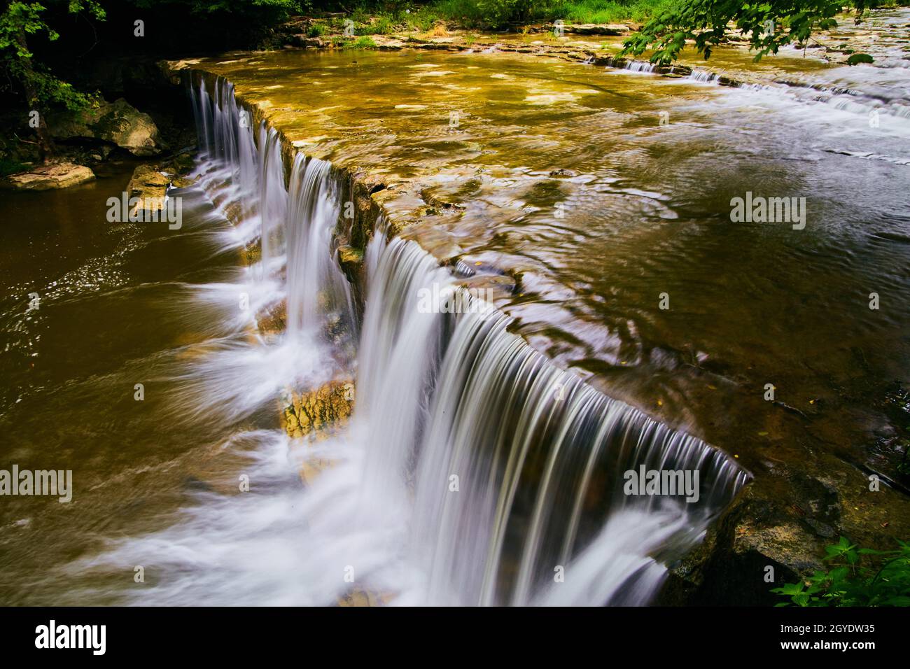 Peaceful waterfalls edge up close flowing into shallow river Stock ...