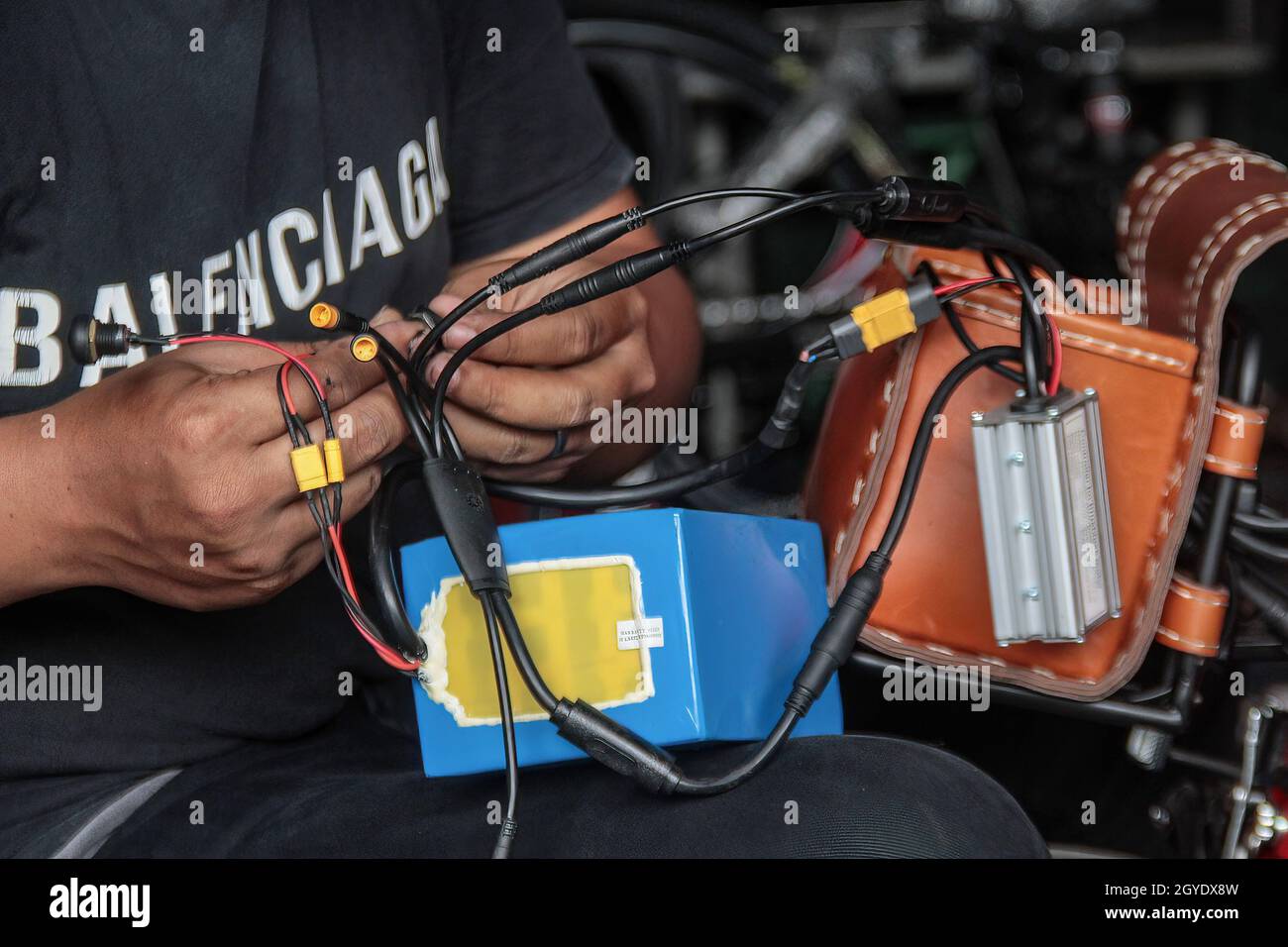 A mechanic seen installing a battery compartment on a folding bicycle ...