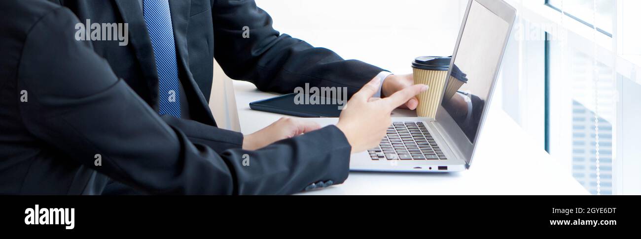 A salesperson in a suit presents the product through laptop computer to ...