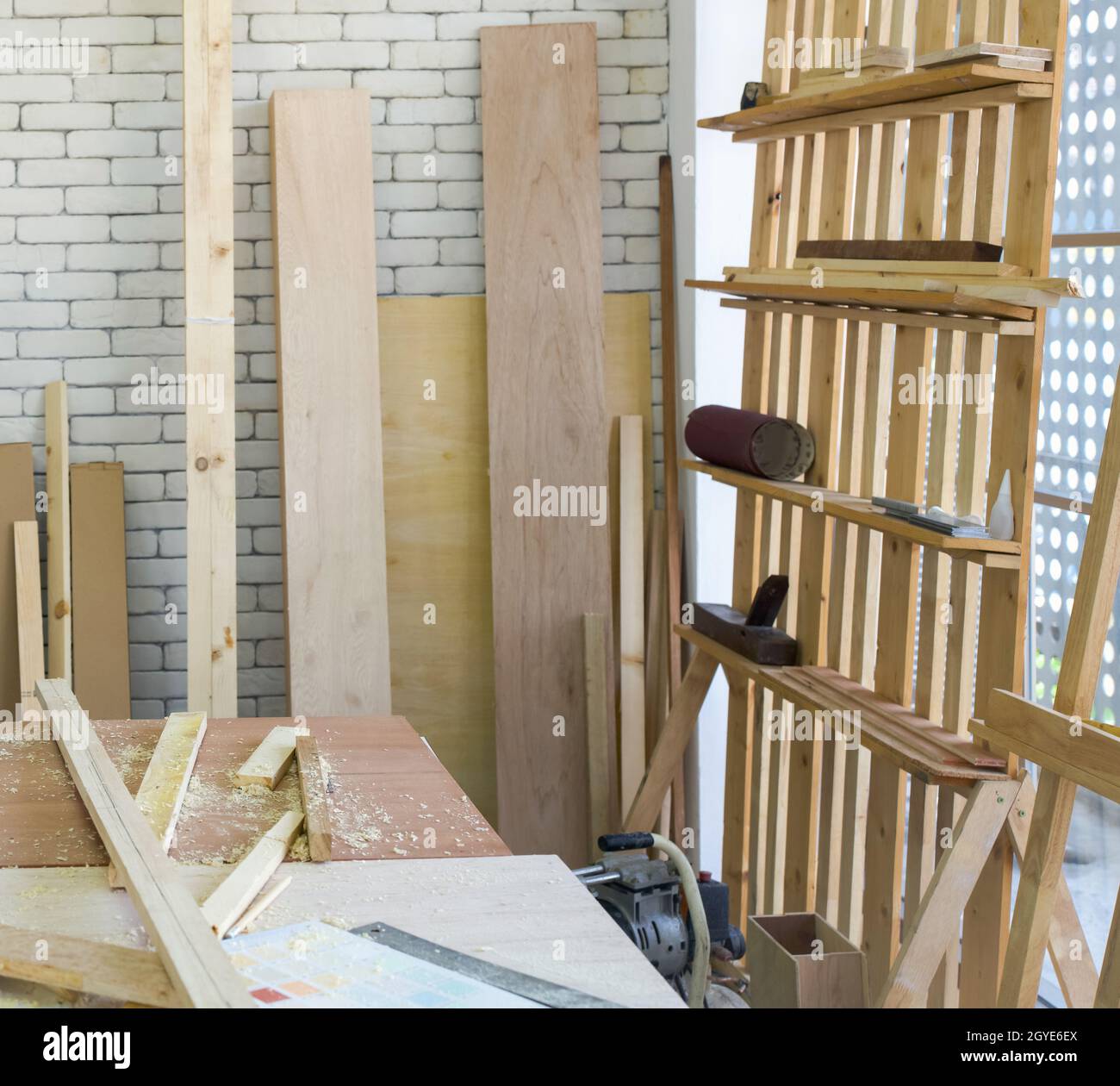 A desk full of wood piles. Wood planks of various sizes lean on a white ...