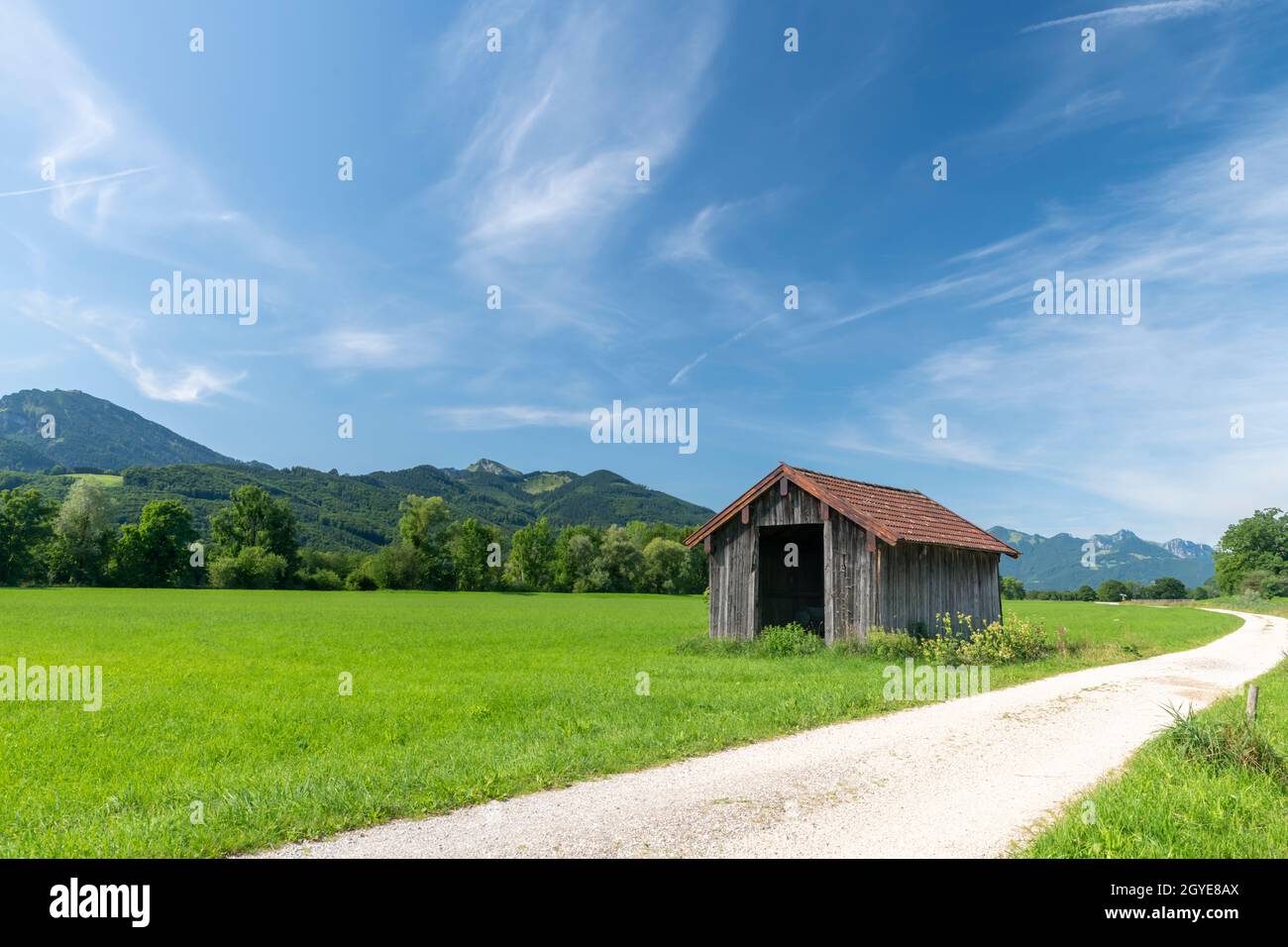 Bavarian meadow landscape with wooden hut, light path, blue sky and ...