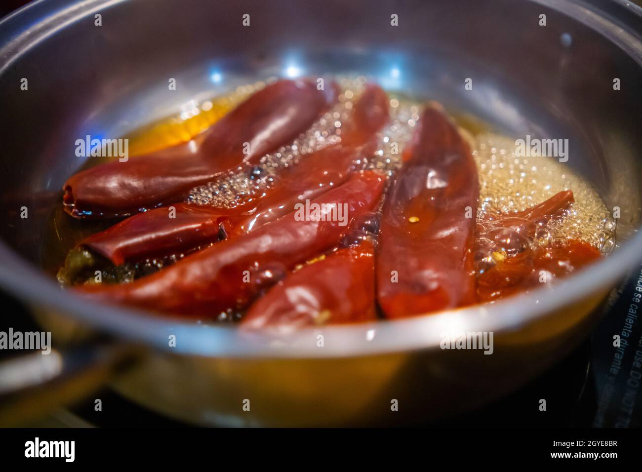 Red dry peppers boiling in oil inside cooking pot Stock Photo - Alamy