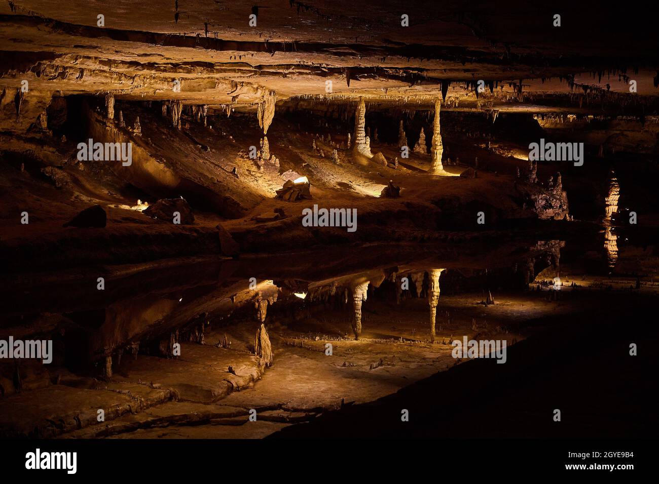 Large reflective pond that looks like a mirror in cave with stalagmites ...