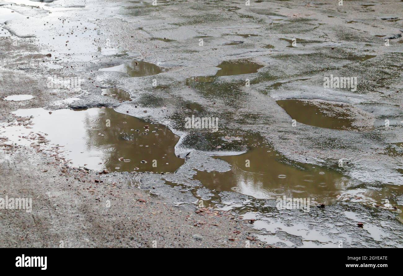 A water-filled hole in an asphalt road. A rainy day in a big city, cars ...