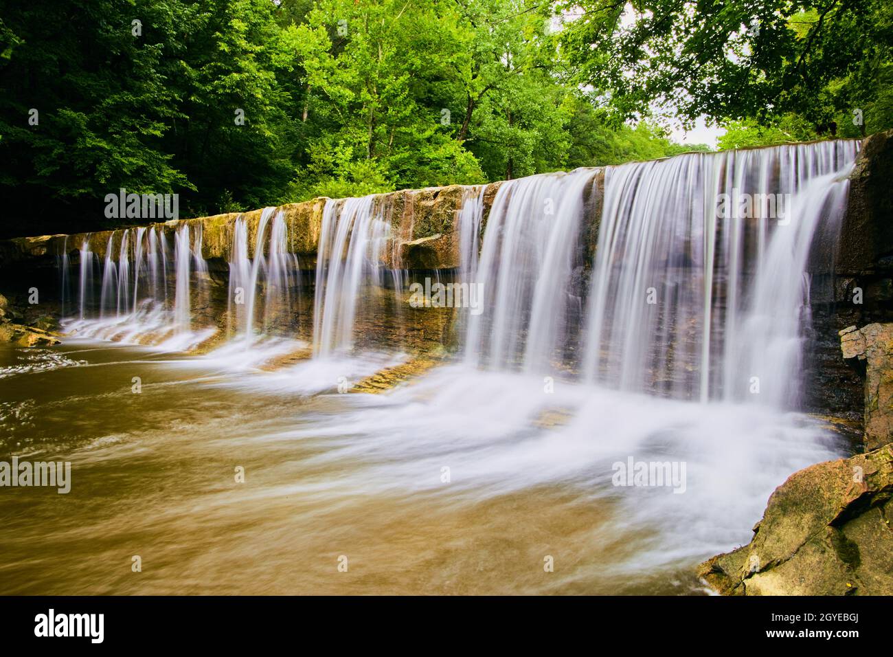 Eye level view of waterfalls flowing over cliff edge into river ...