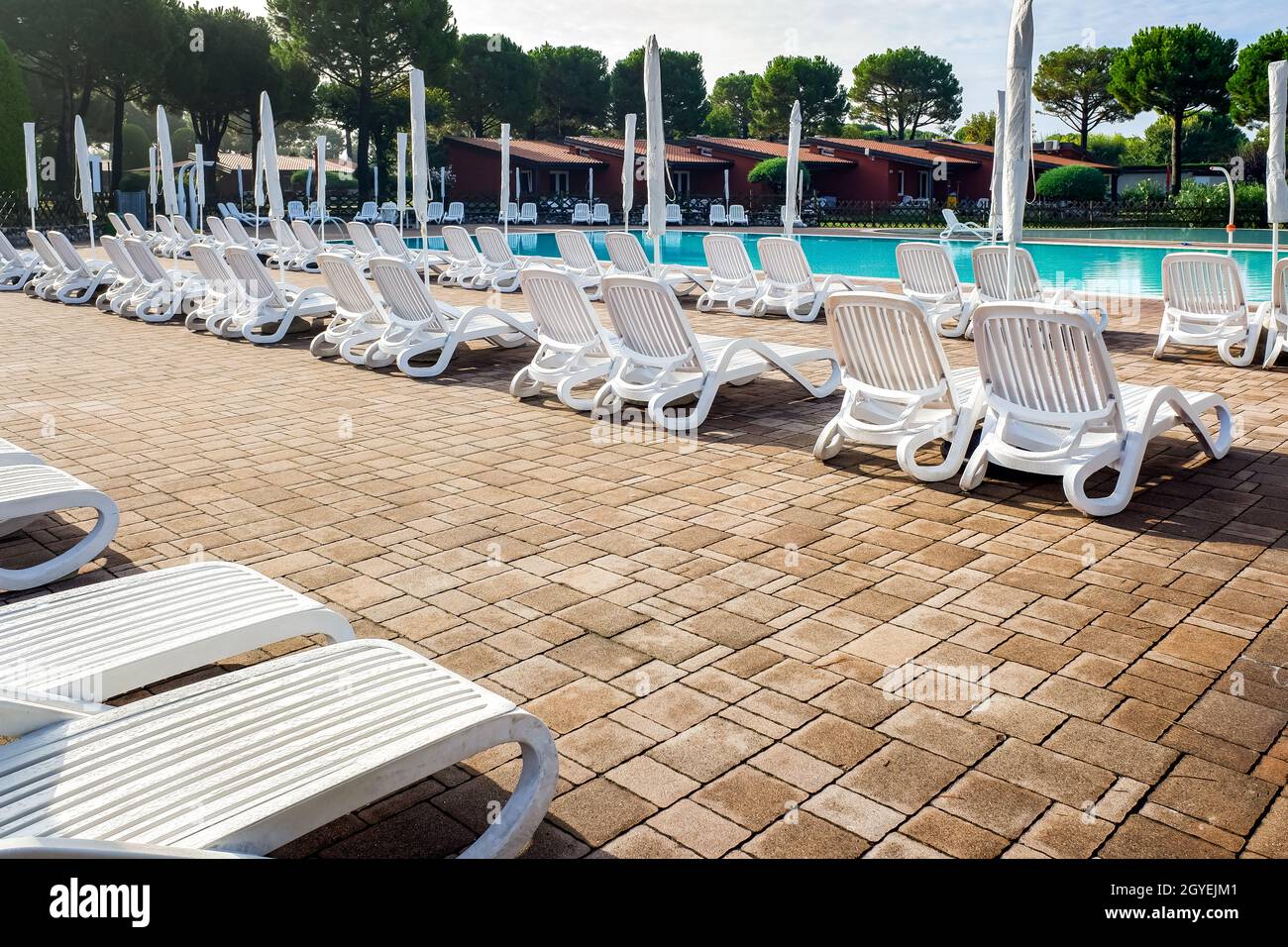 Empty plastic sunbeds without tourists in an outdoor swimming pool ...