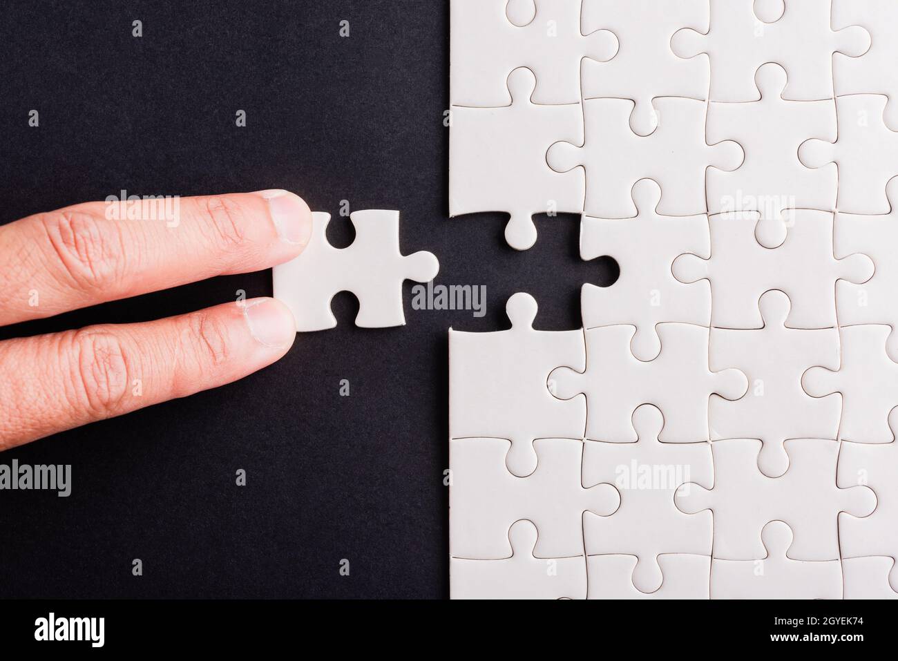 Top view flat lay of hand-holding last piece white paper jigsaw puzzle ...