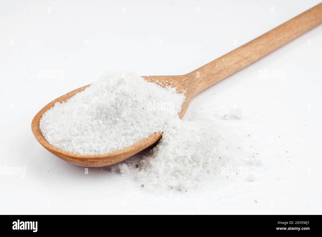 Rock salt in a wooden spoon on a white background Stock Photo - Alamy