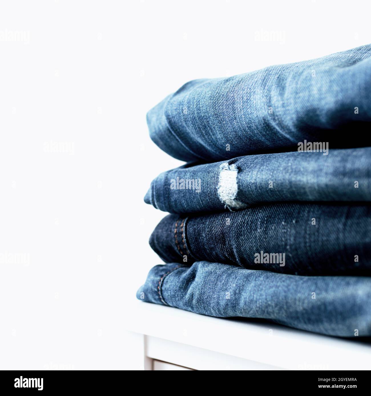 Stack of different blue denim jeans trousers on the shelf or table ...