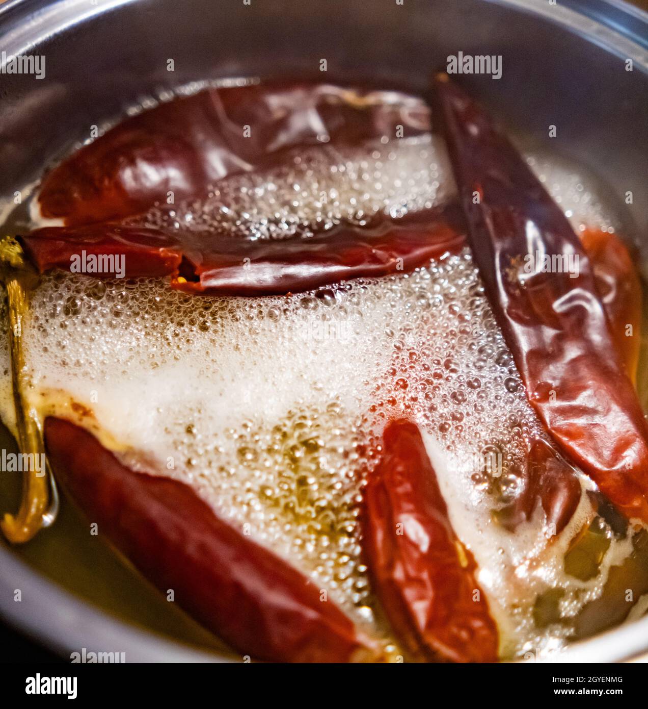 Red dry peppers boiling in oil inside cooking pot Stock Photo - Alamy