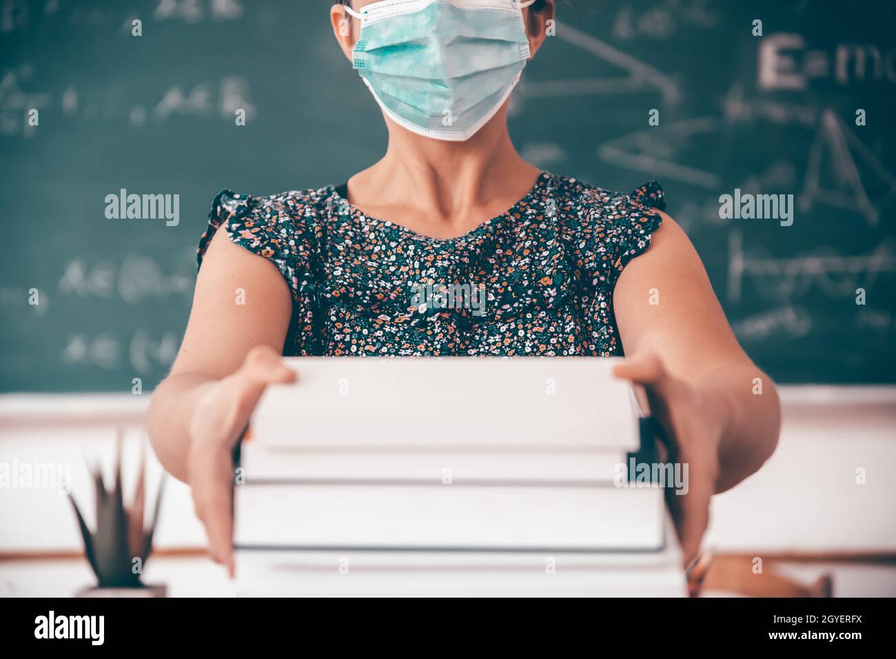 Teacher with face mask welcoming children back at school after lockdown ...