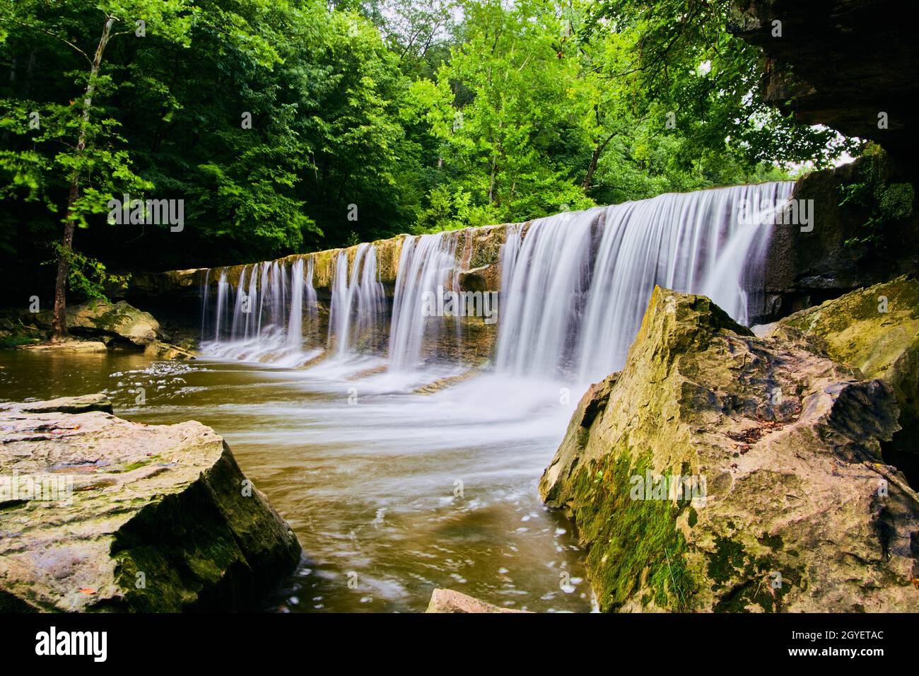 View of waterfalls over cliffs between two large boulders Stock Photo ...