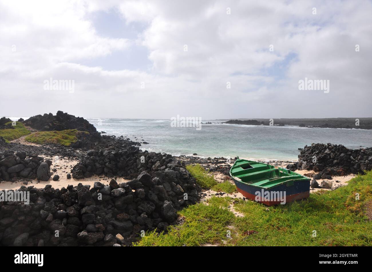 Lava rocks and fishing boat on remote beach of spanish island Lanzarote ...